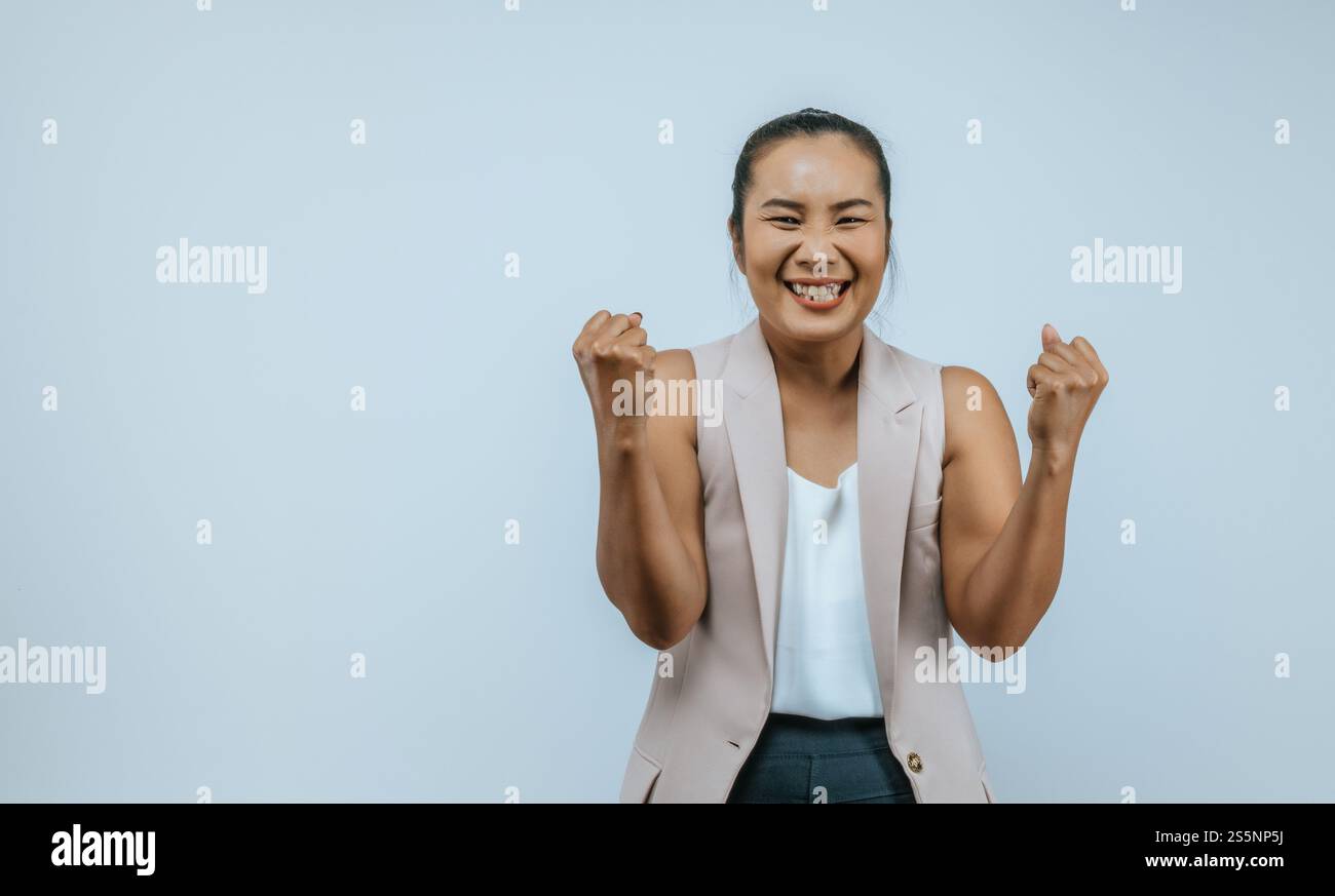 Emotive excited Asian woman keeps hands clenched in fists, exclaims ...