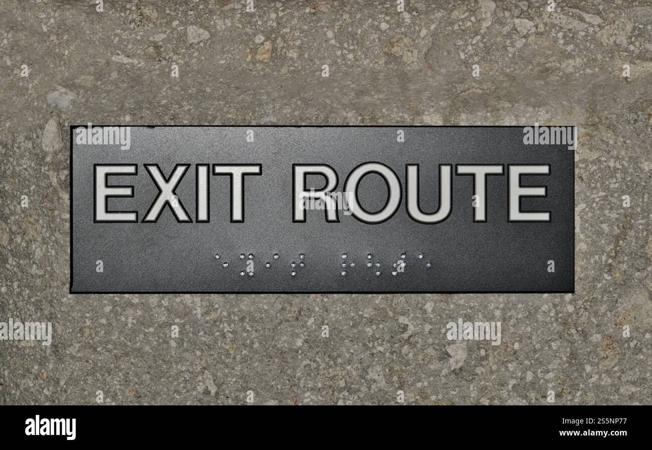Exit route sign with braille symbols concrete wall interior evacuation ...