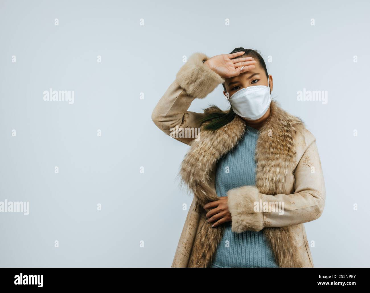 Portrait of Asian woman wearing a fur coat, putting on protective mask ...
