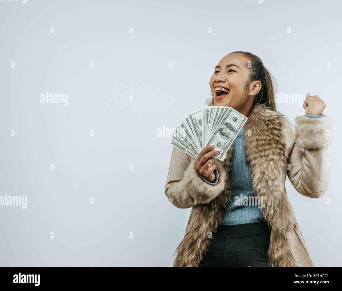 Portrait of successful Asian woman with a fur coat holding money in ...