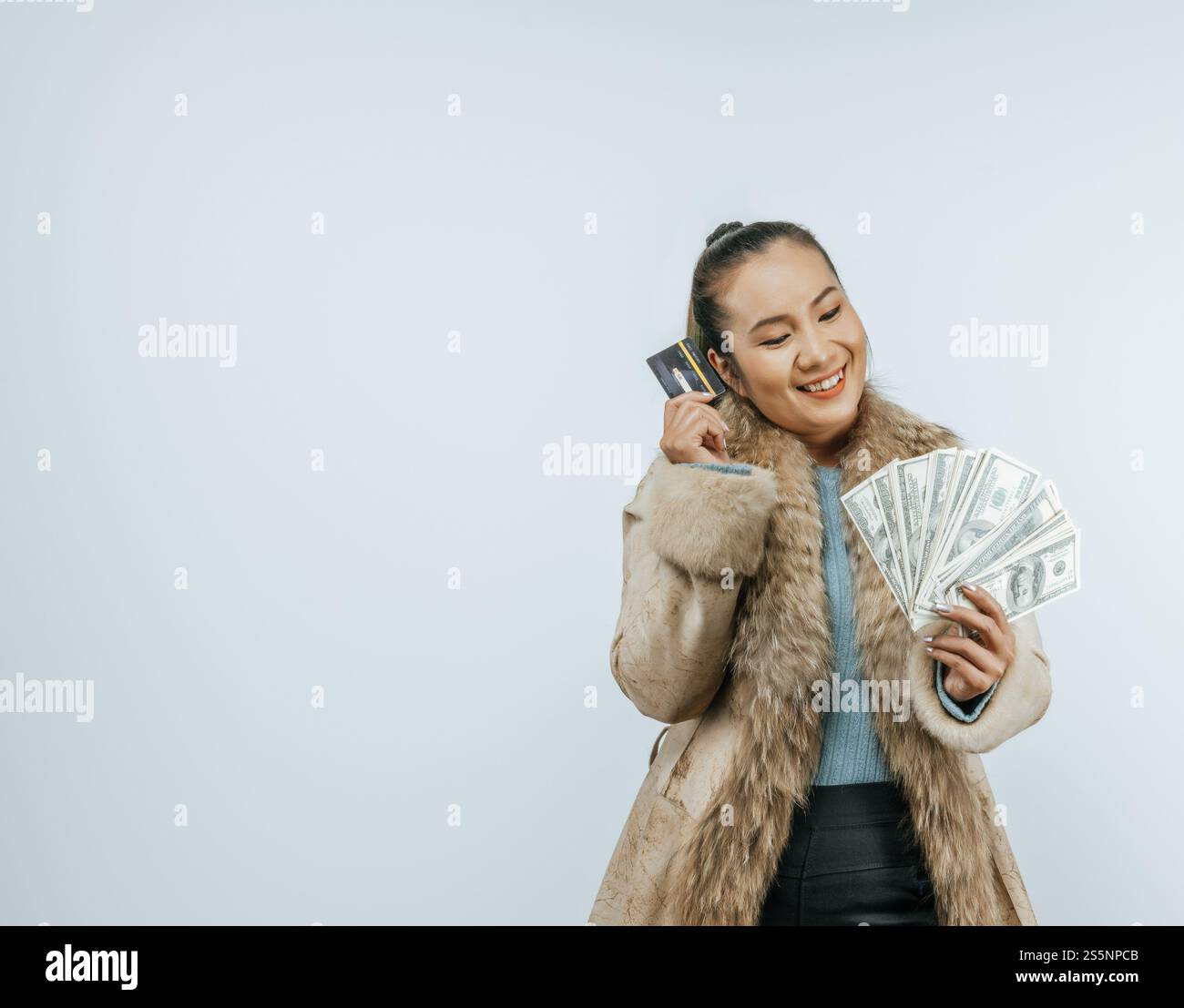 Portrait of successful Asian woman with a fur coat holding money and ...