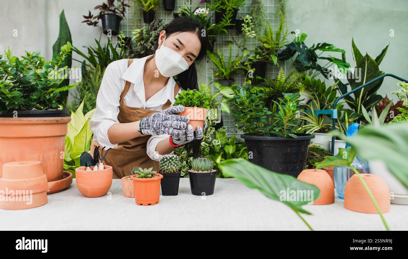 Asian gardener woman wearing face mask and apron holding green ...