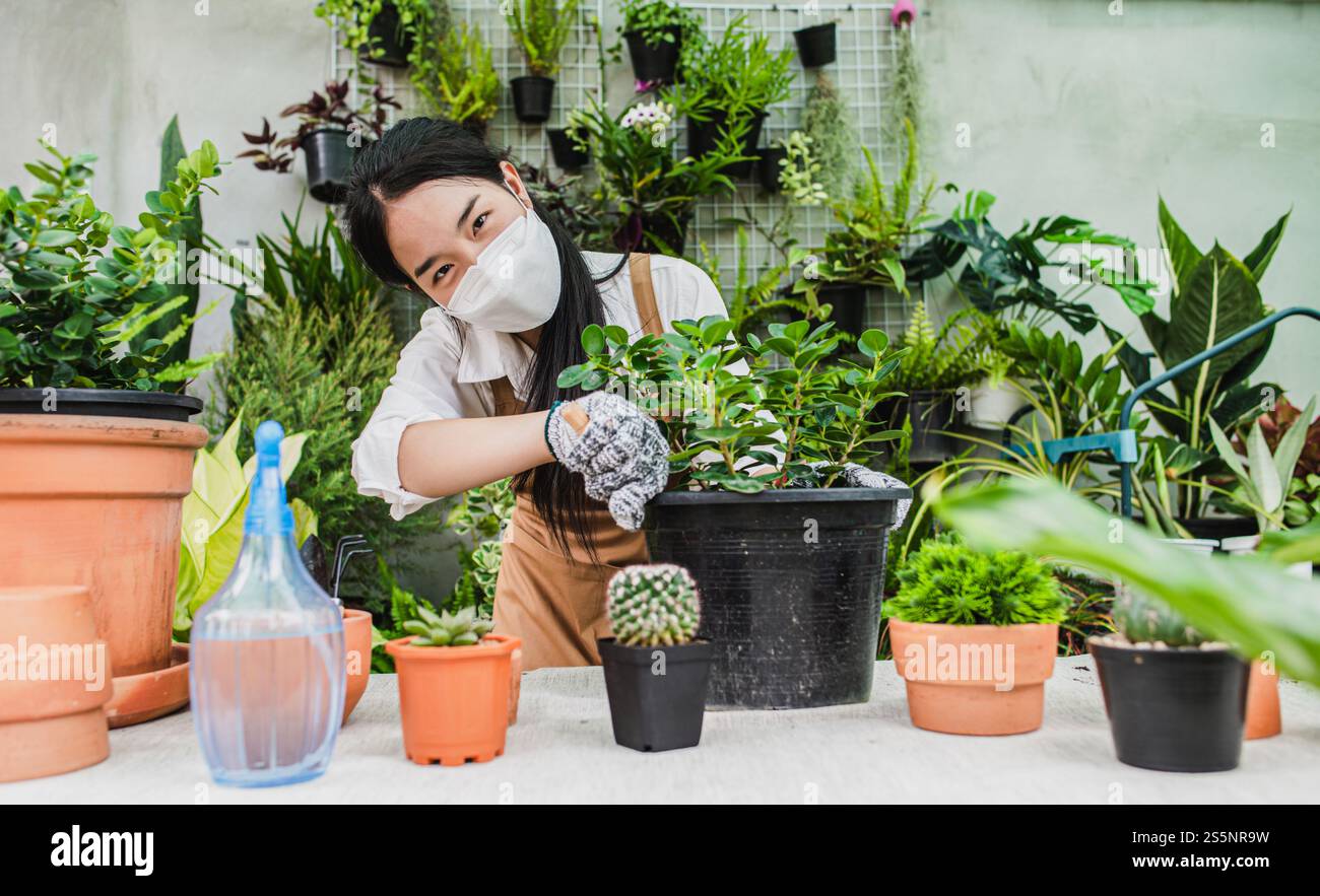 Asian gardener woman wearing face mask and apron using shovel to ...