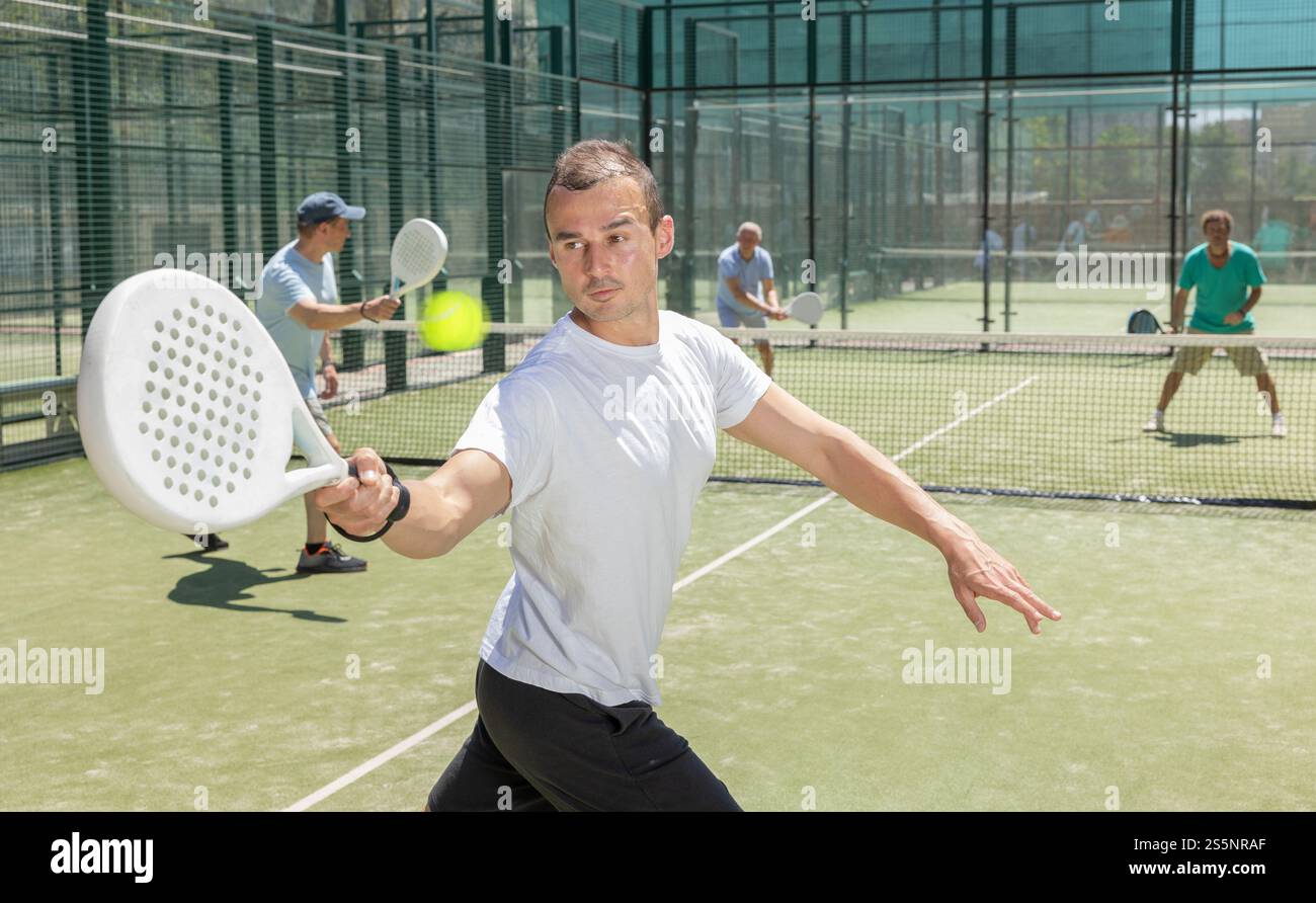 Active man engaged in padel in open-air court of tennis club Stock ...