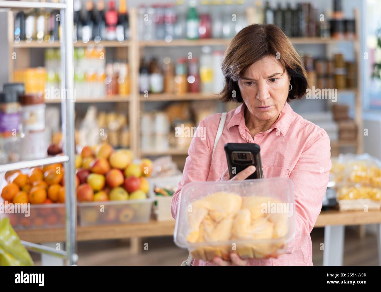 Female purchaser scanning QR code or barcode of chicken thighs in shop ...