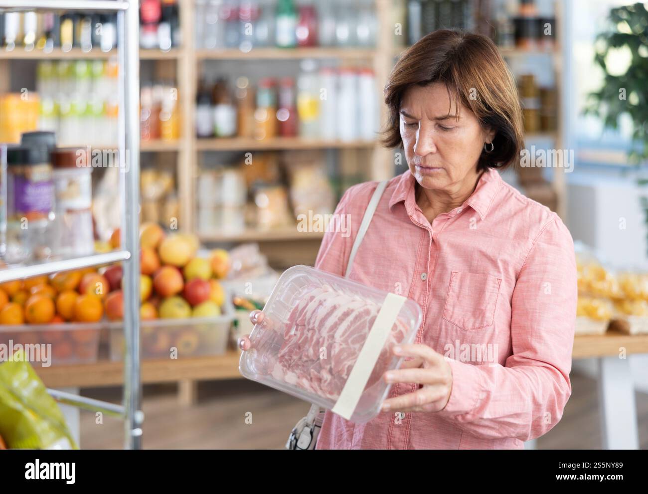Female customer chooses a pork loin in the produce section of ...