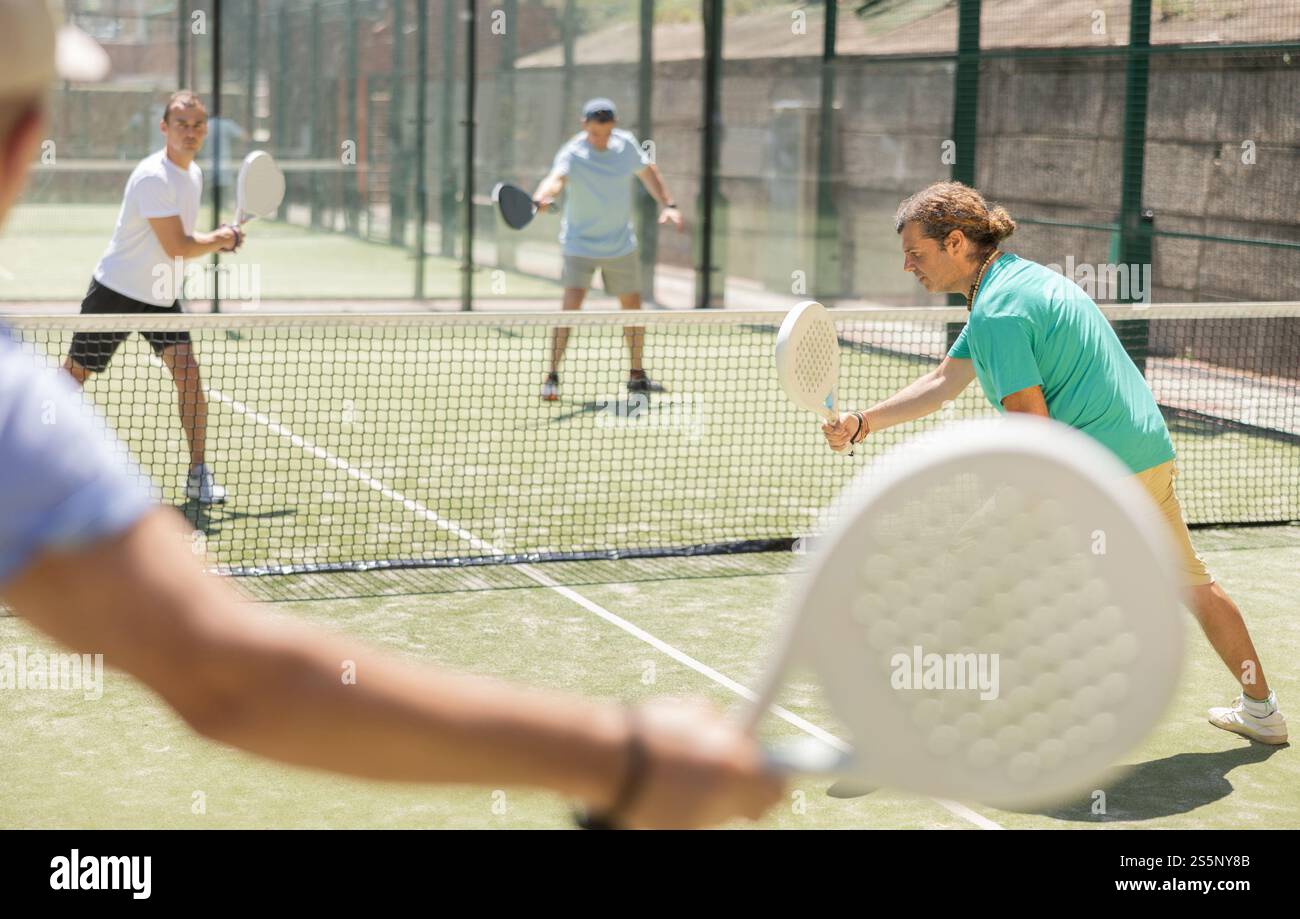 Adult and elderly men playing padel against two men Stock Photo - Alamy