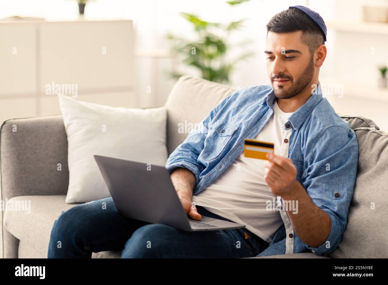Jewish guy using pc and credit card at home Stock Photo - Alamy