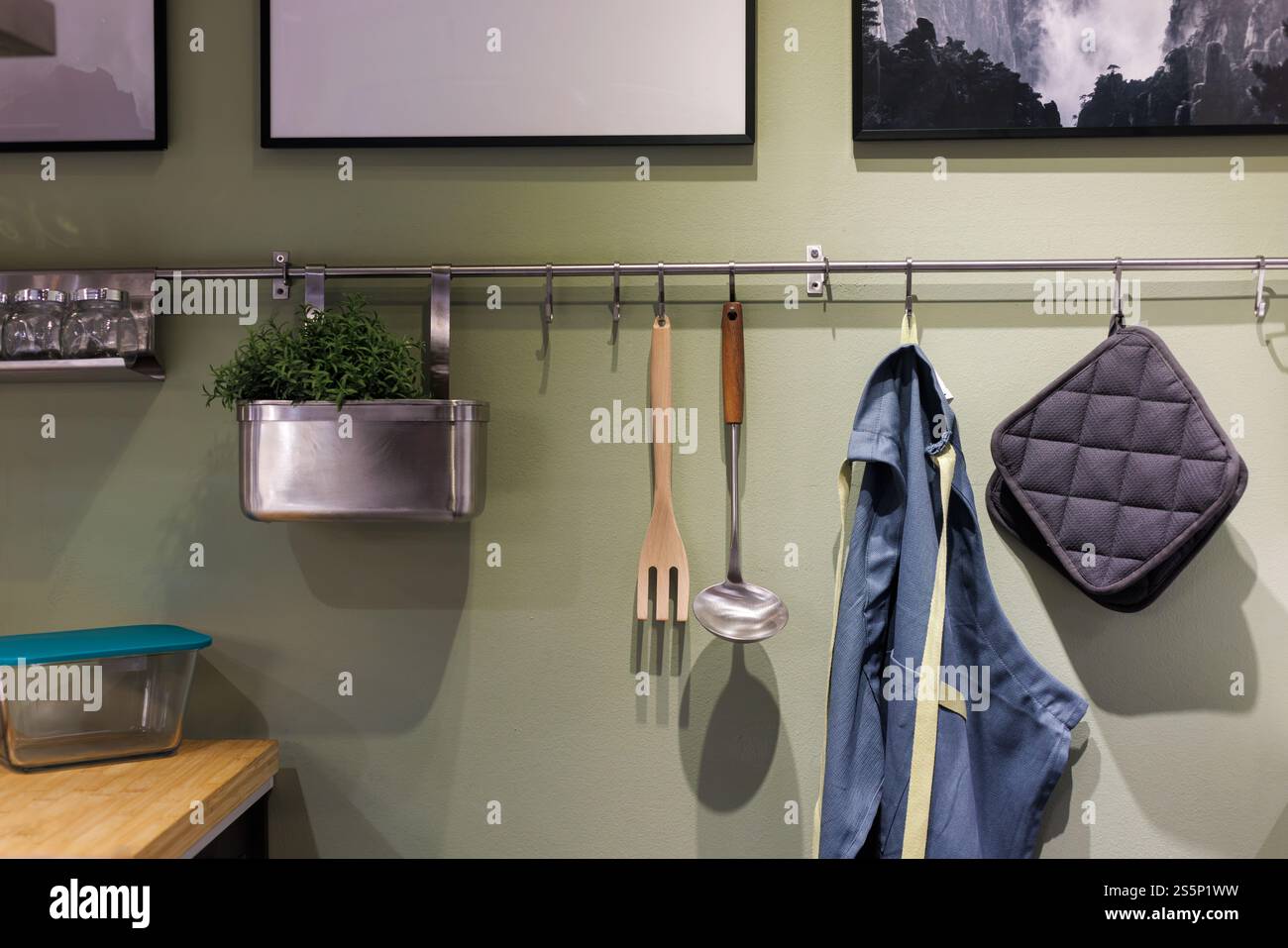 Kitchen set on green wall. Cooking utensils hanging on metal rack in ...