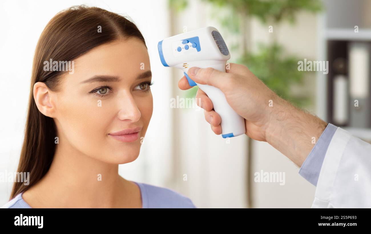 Doctor checking temperature of female patient using infrared ...