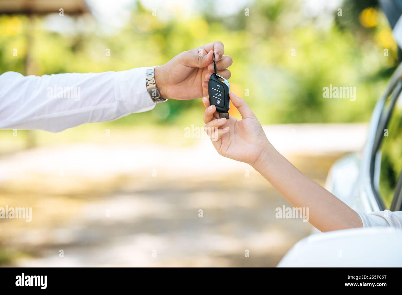 A woman sits in a car and holds out her hand to receive the car keys ...