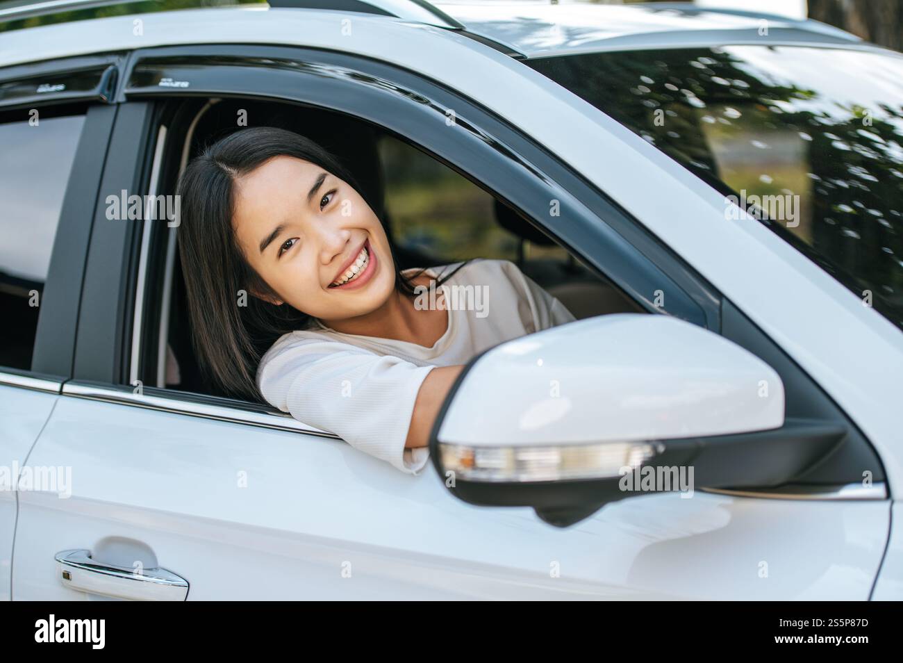 A woman driving the car smiles happily and opens the window Stock Photo ...