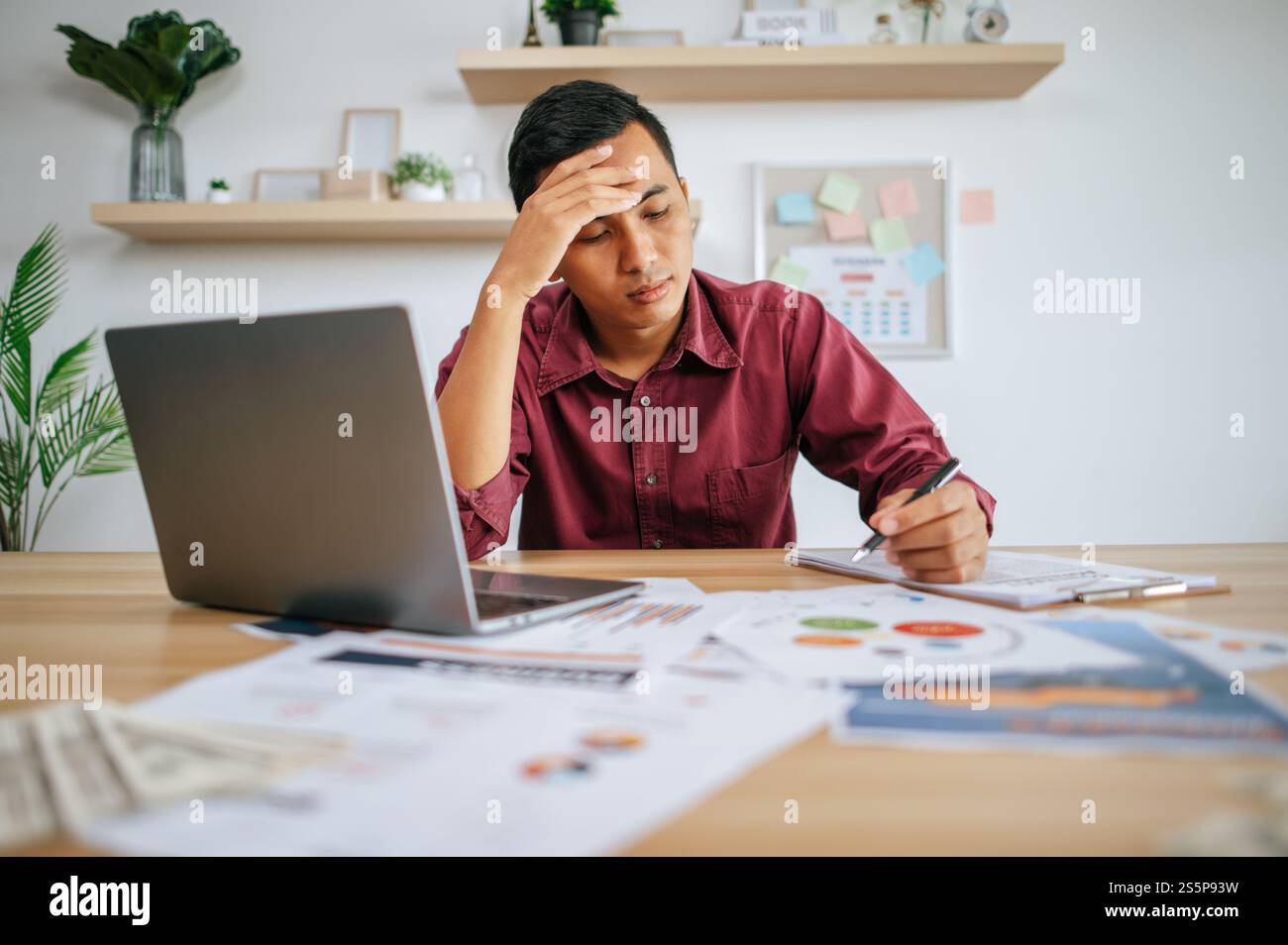 Man working with laptop and paperwork with stress Stock Photo - Alamy