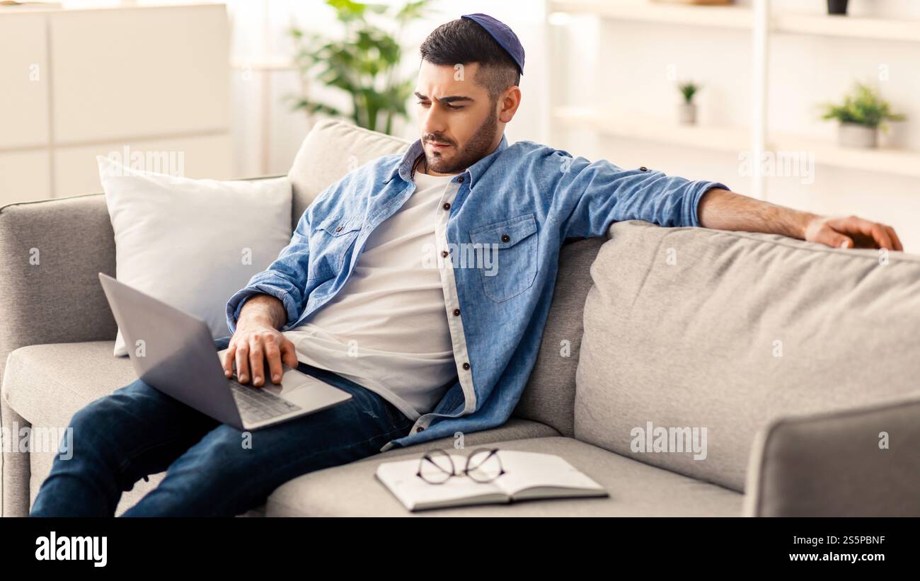Jewish man working on computer, sitting on couch Stock Photo - Alamy