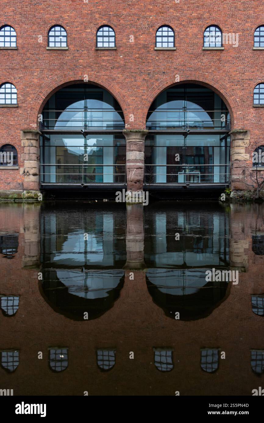 A historic brick building with arched windows reflecting perfectly on ...