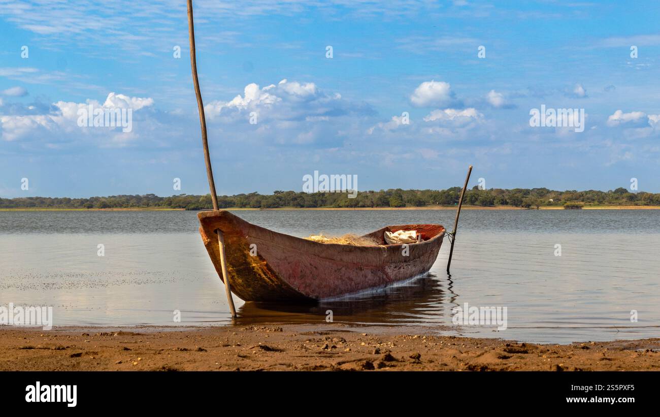 A close-up of a rustic wooden fishing boat tethered to the shoreline of ...