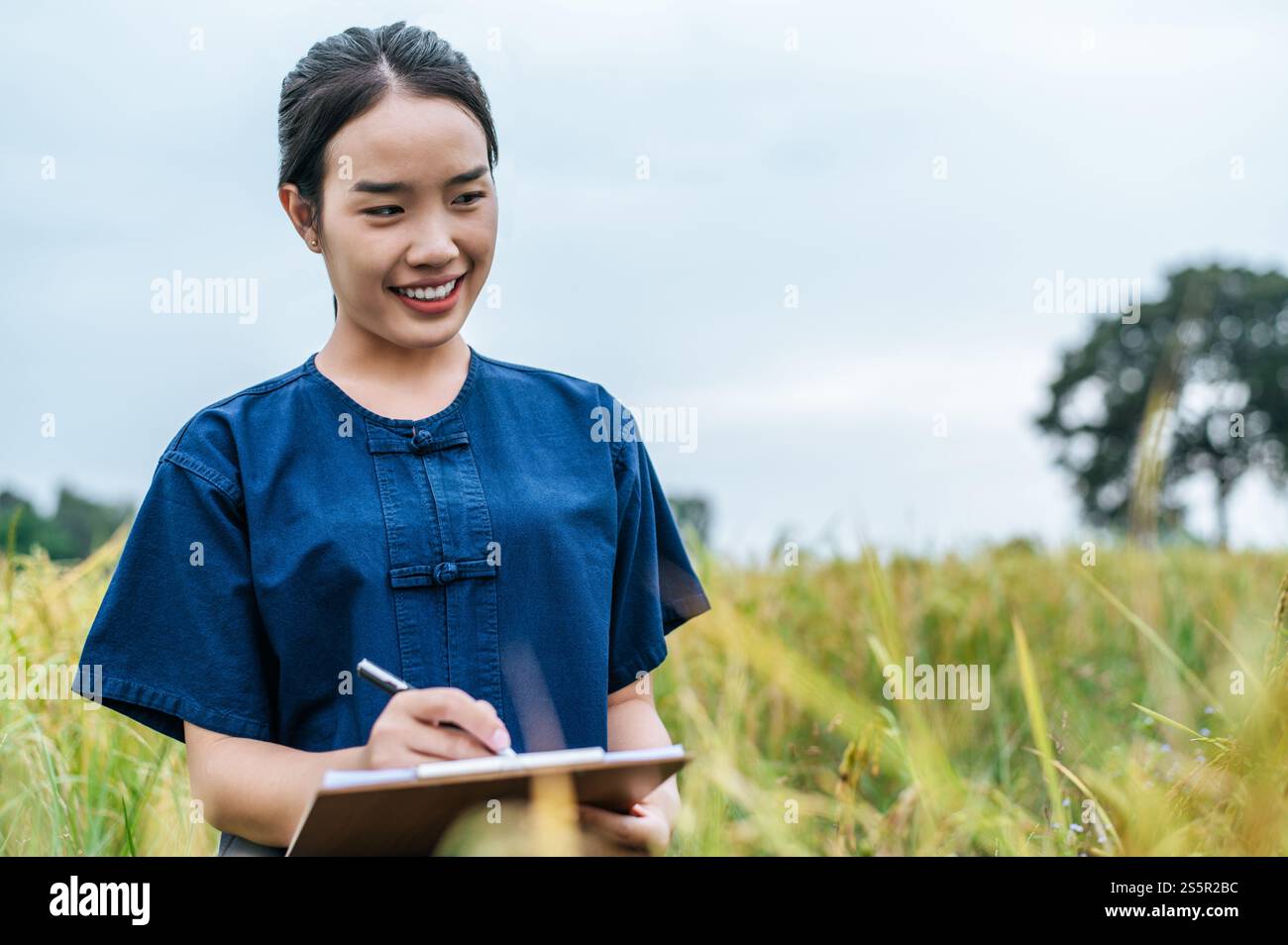 Protrait Asian Young farmer woman writing on clipboard during work on ...