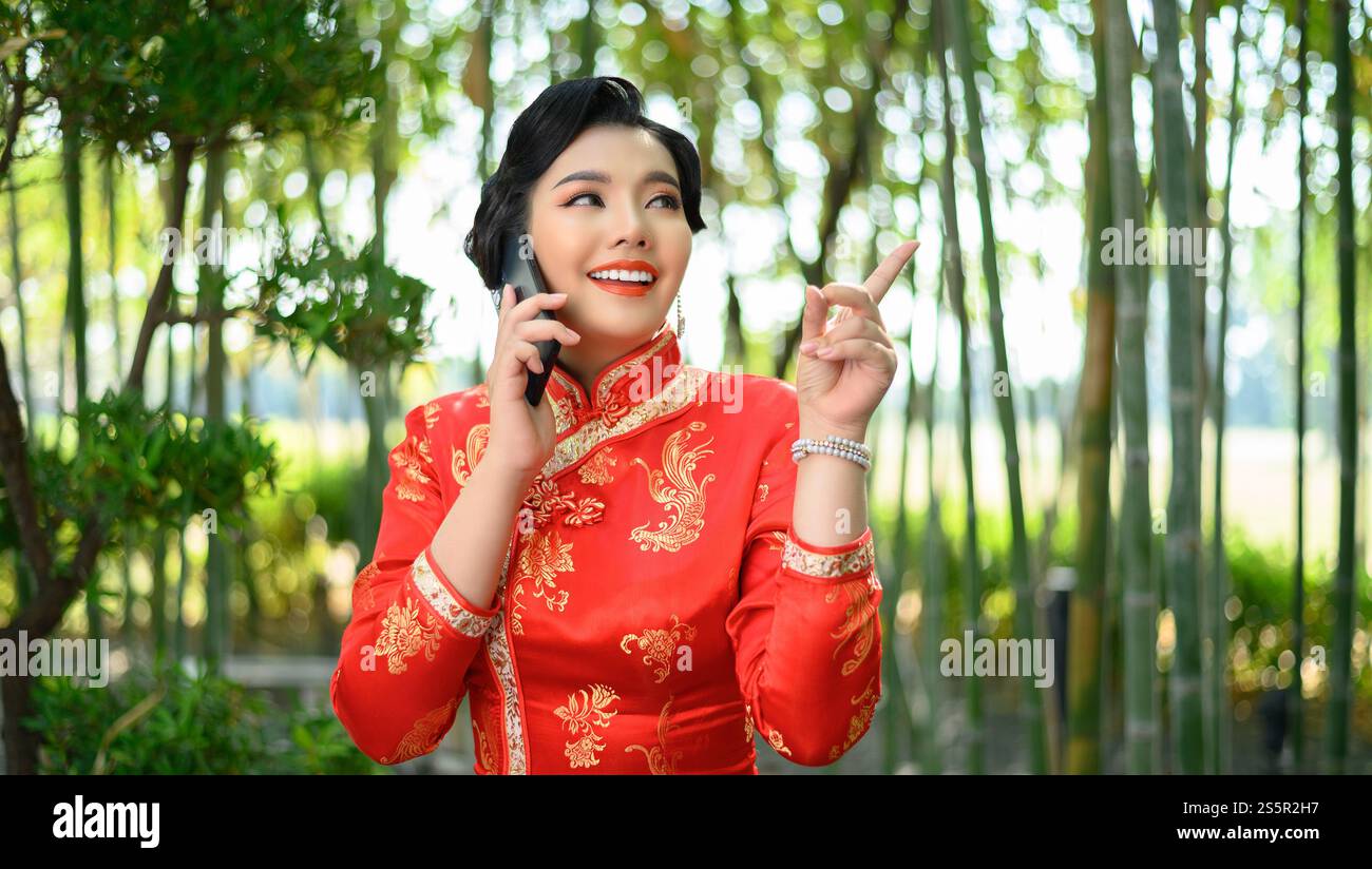 Portrait pretty Asian woman in a Chinese cheongsam smile and point ...