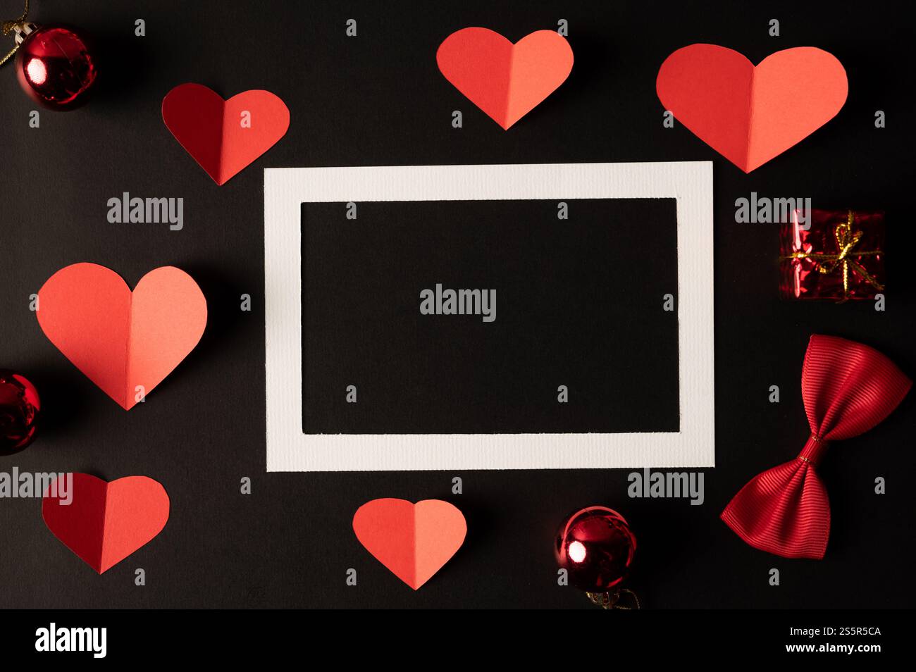 White photo frame and red heart paper pasted on a black background ...