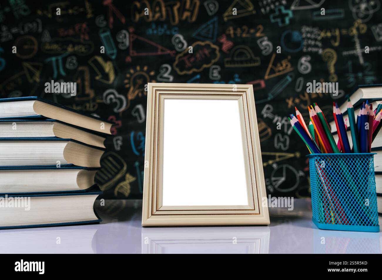 white photo frame, book and colored pencils in classroom Stock Photo ...