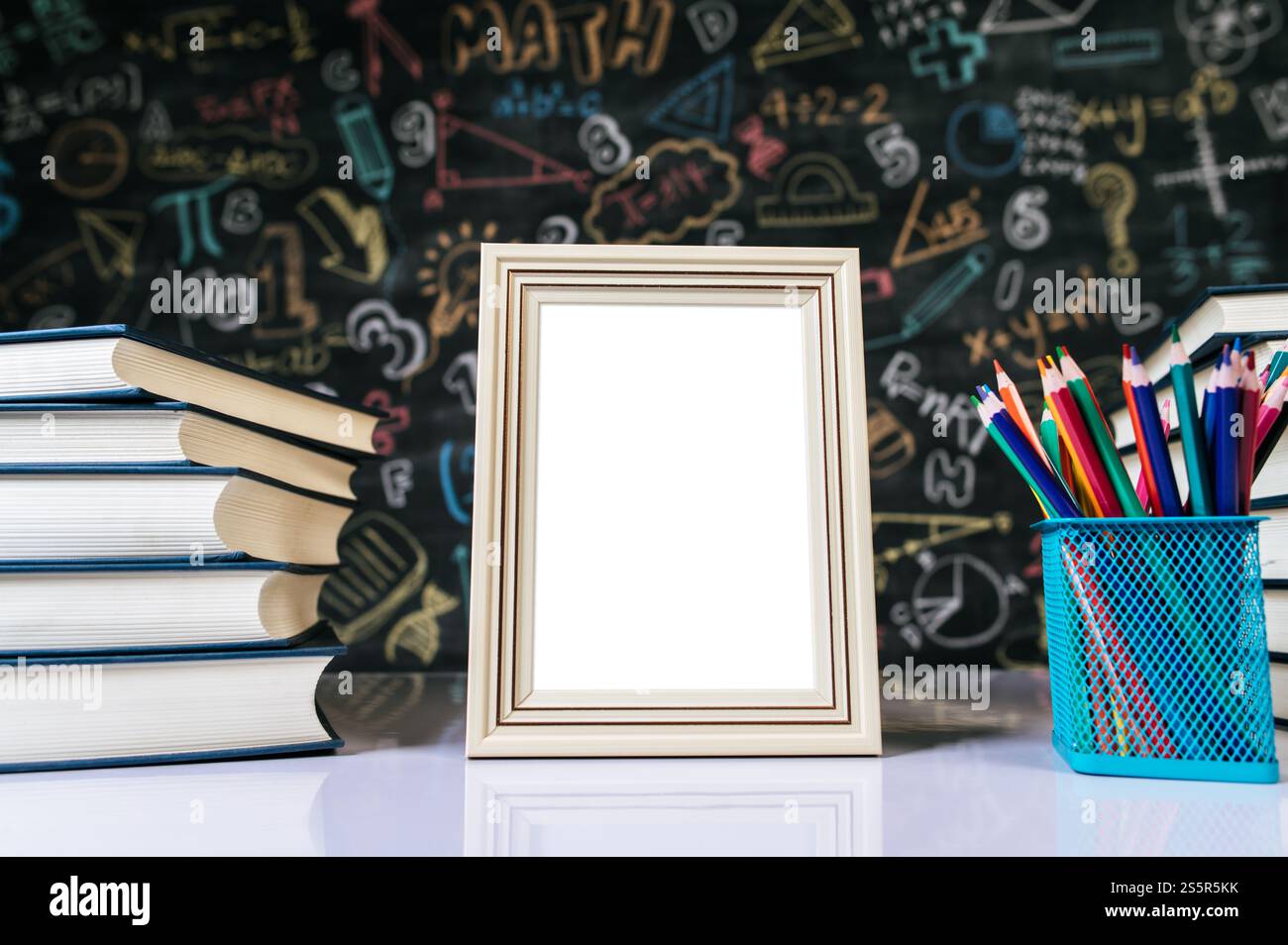 white photo frame, book and colored pencils in classroom Stock Photo ...
