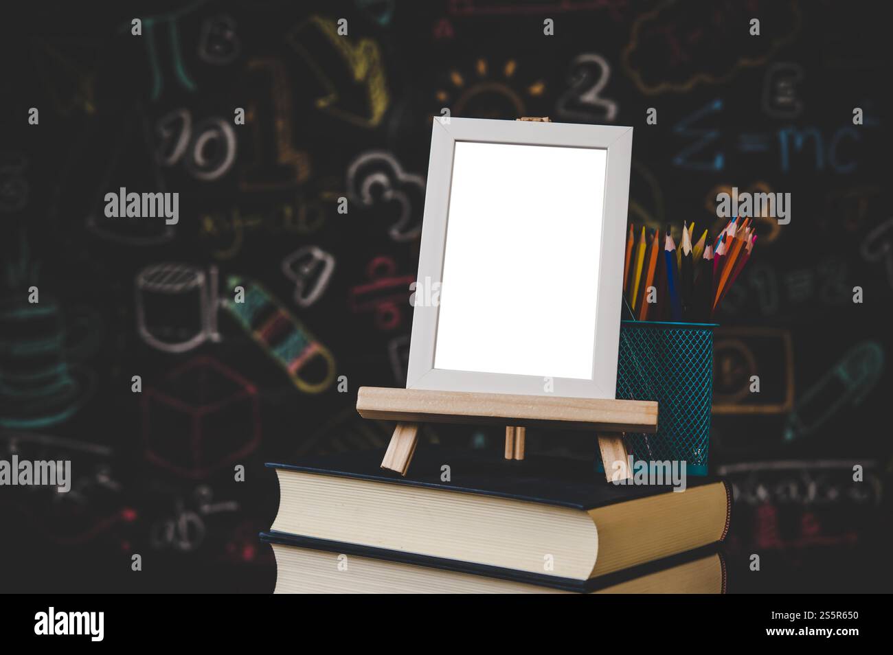 white photo frame on the stand and colored pencils on the books in ...