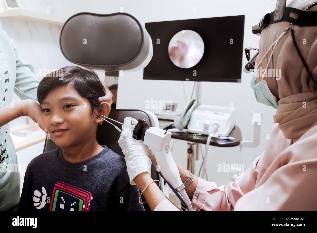 Asian boy ear being examined by a female doctor using medical otoscope ...