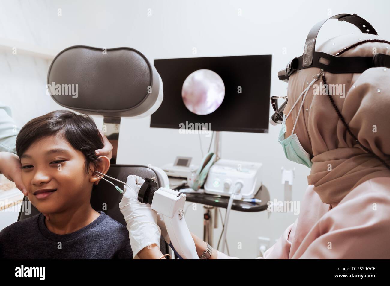 Asian boy ear being examined by a female doctor using medical otoscope ...