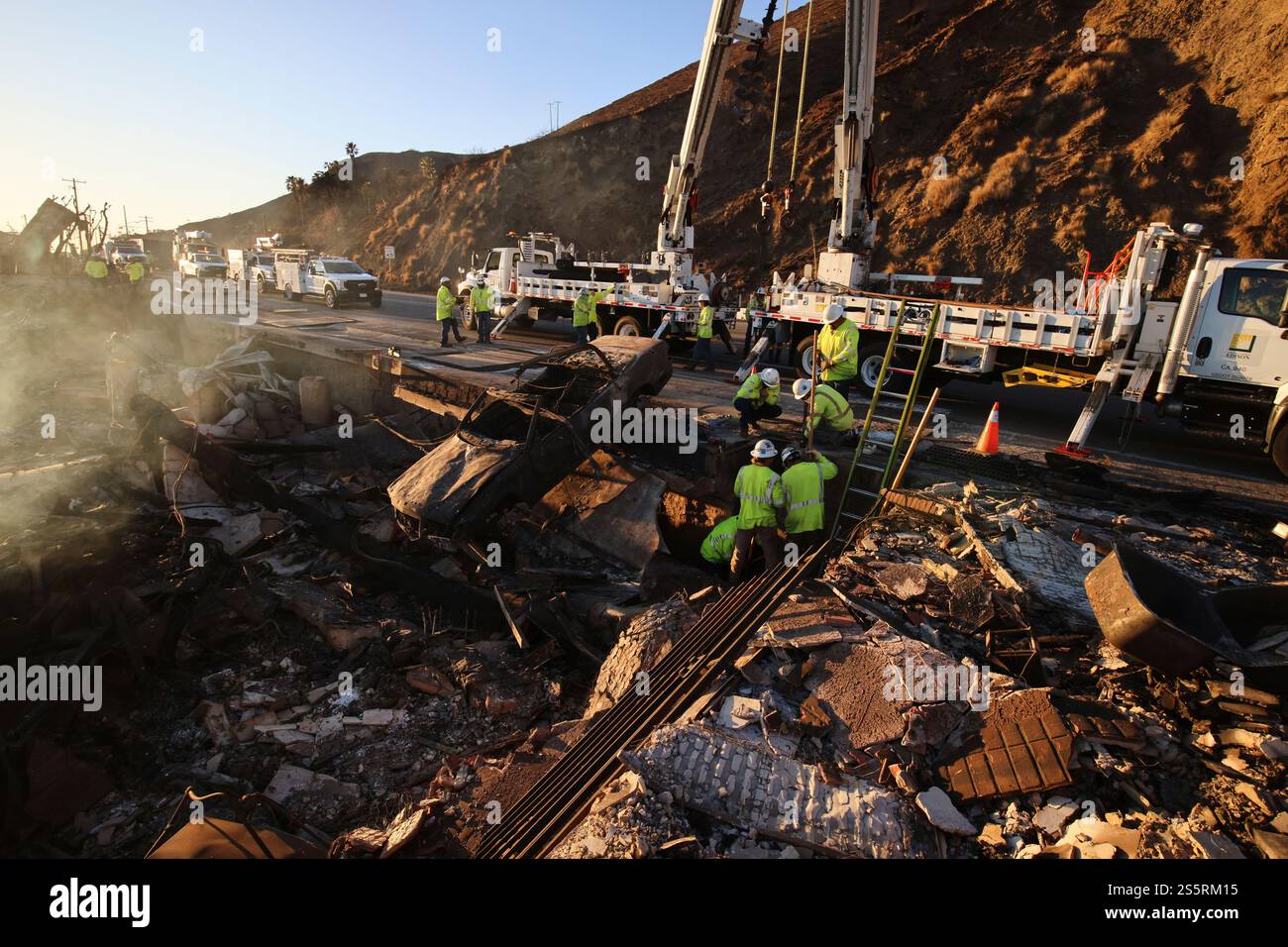 Workers pull a burnt car out of the wreckage of a home destroyed by the ...