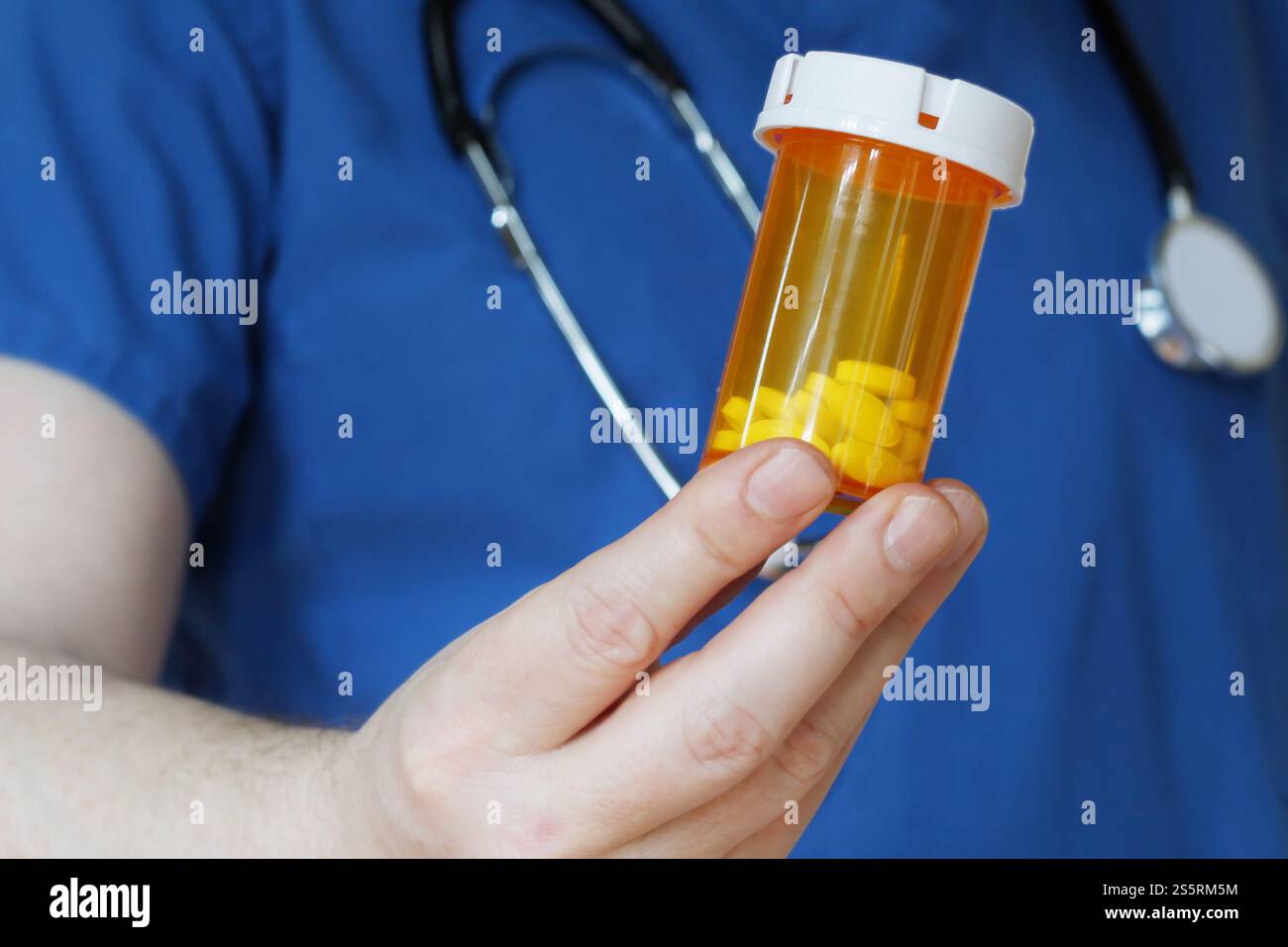 Closeup medical professional in blue scrubs holding pill bottle ...