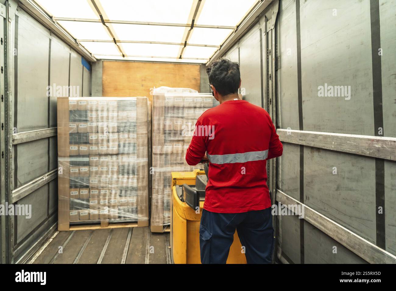 Rear view of a latin male delivery worker loading cardboard cartons on ...