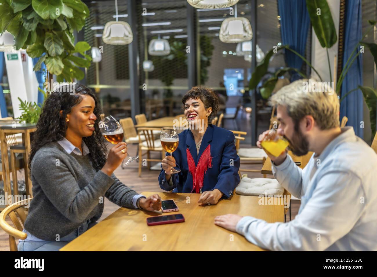 Cool multi-ethnic friends sitting on a bar terrace enjoying beer ...