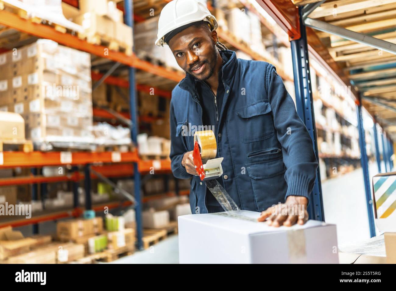 African man closing boxes of merchandise using a tape gun at a ...