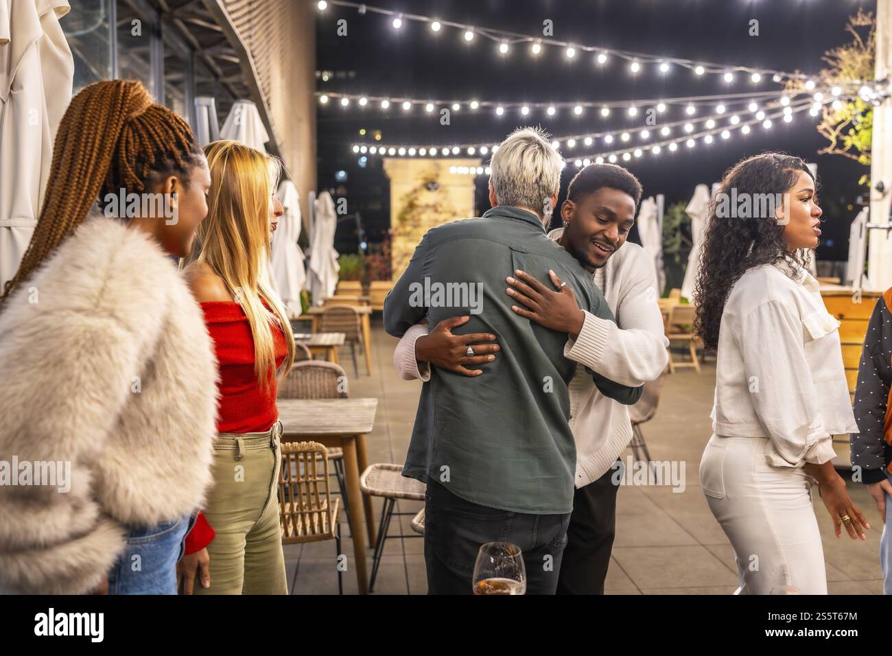 Multi-ethnic friends hugging while arriving in a meeting in a night bar ...