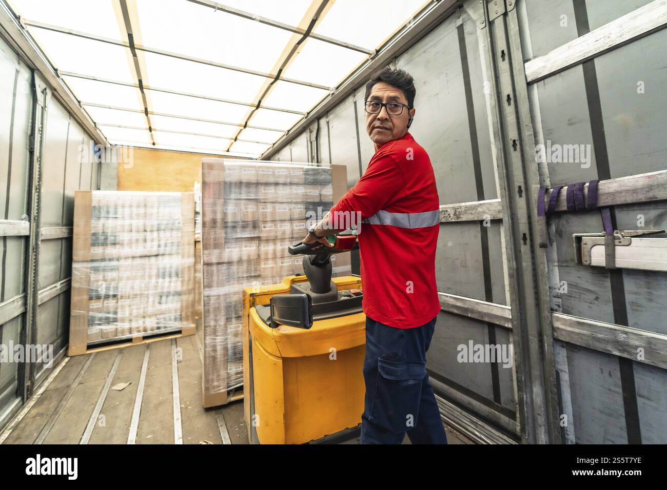 Rear view of a concentrated latin man worker loading a delivery truck ...