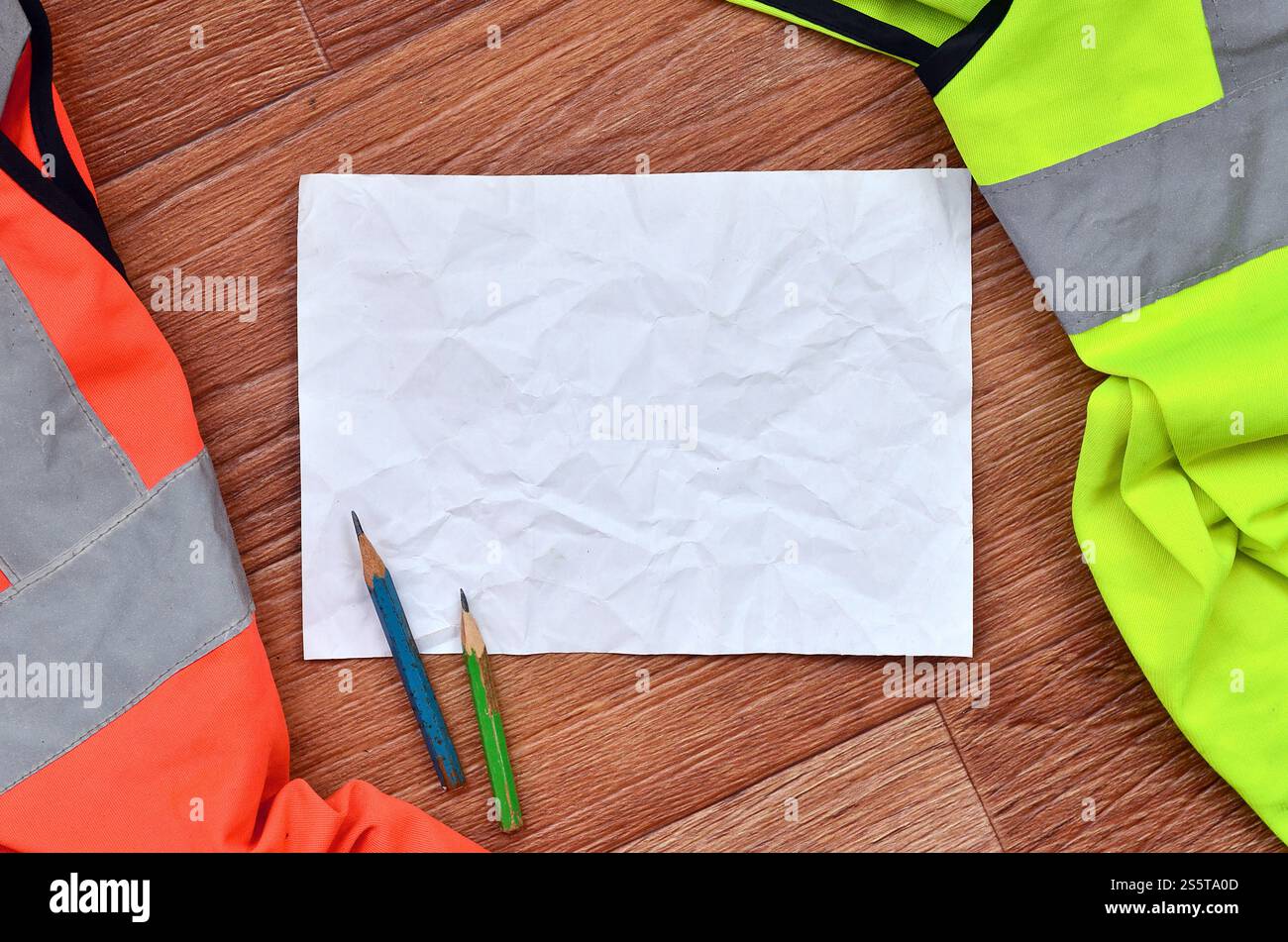 A crumpled sheet of paper with two pencils surrounded by green and ...
