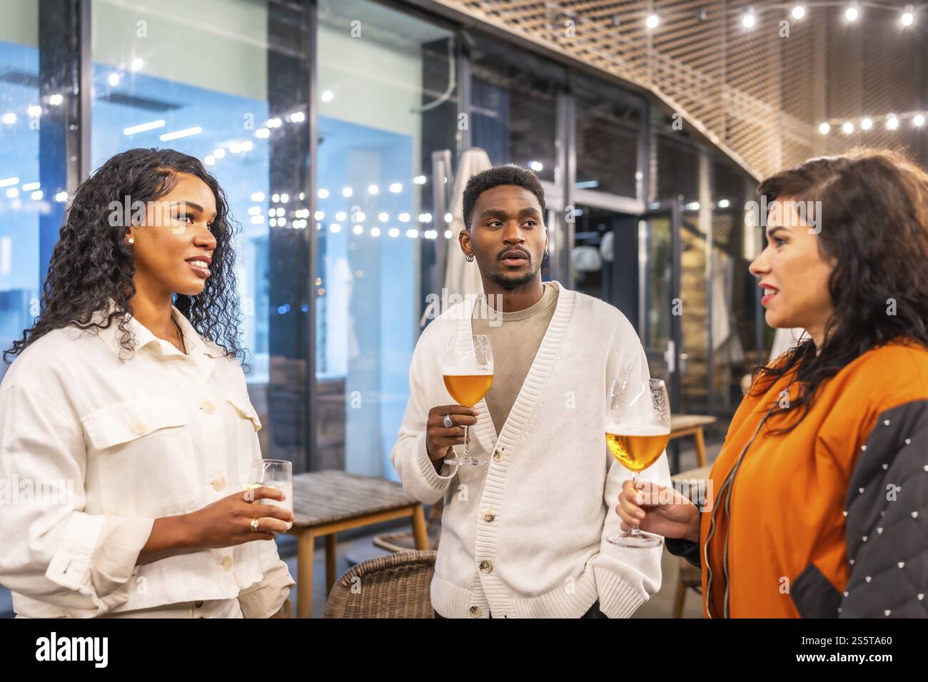 Multi-ethnic coworkers talking while drinking beer in the terrace of a ...