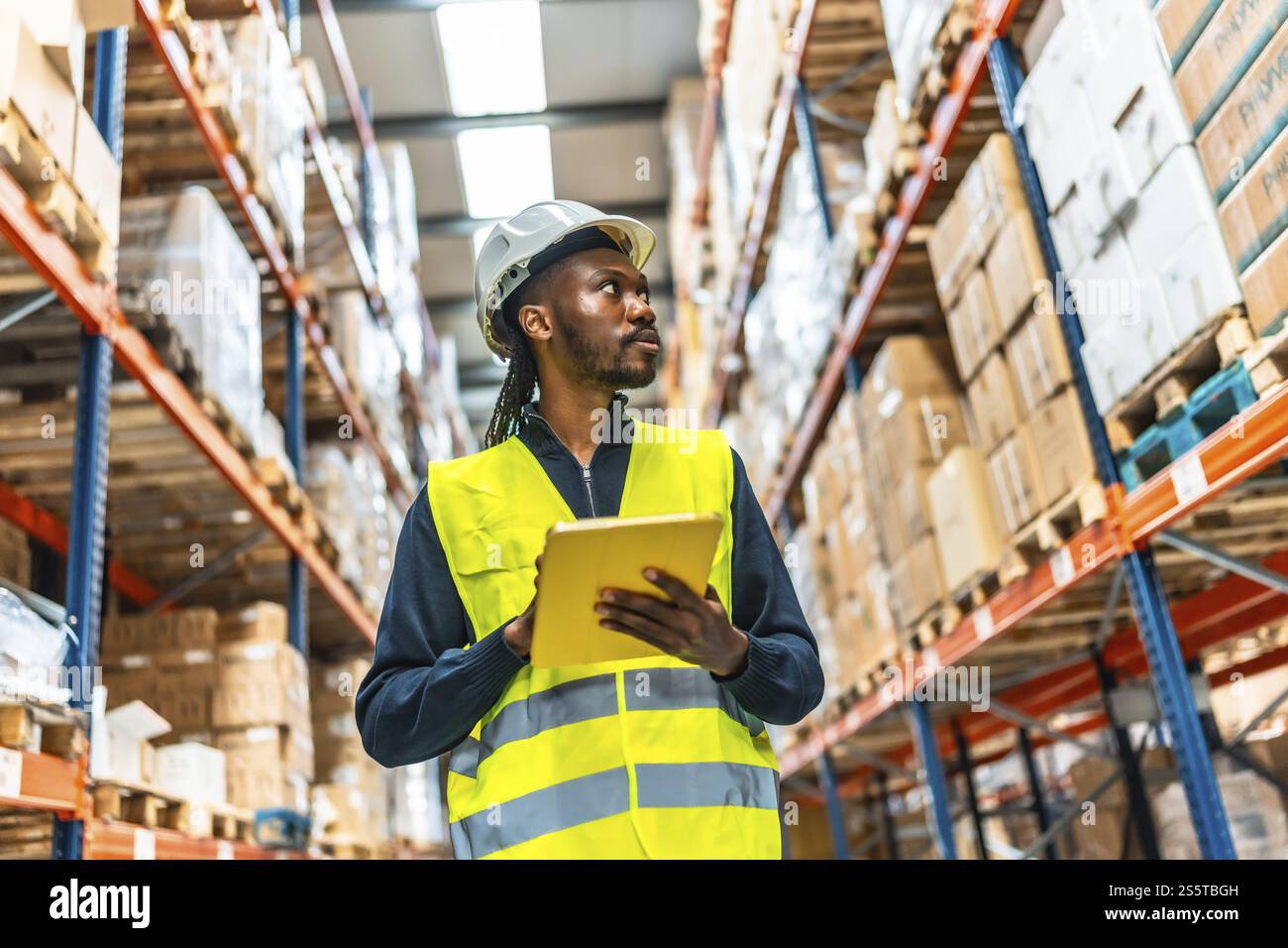 African warehouse supervisor using tablet while working tracking ...