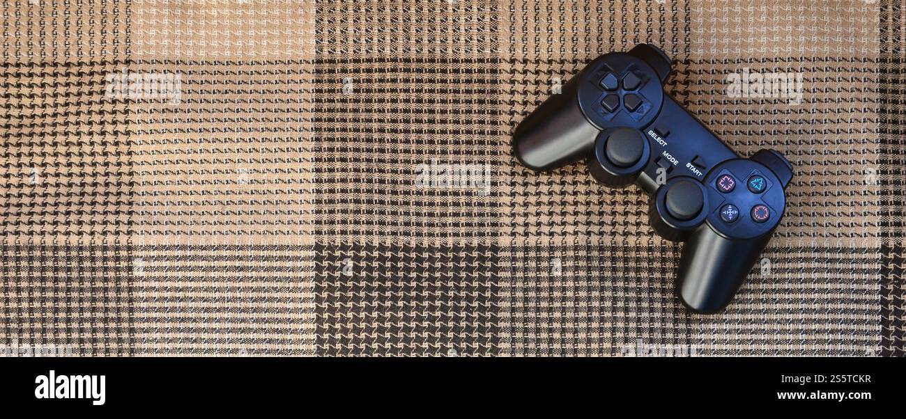 Modern black video game controller lies on a checkered beige and black ...