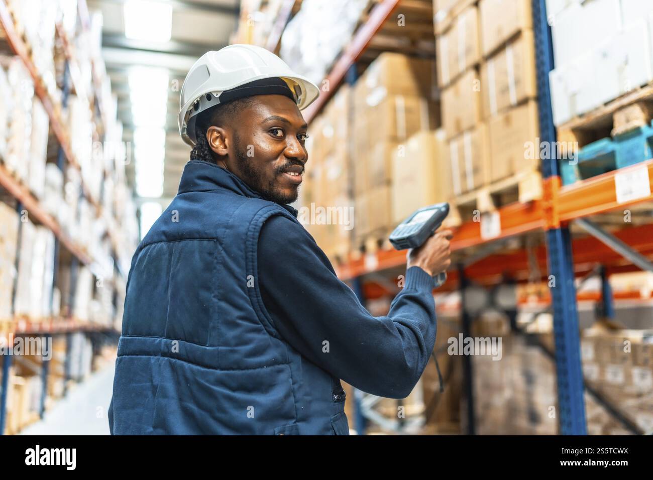 Happy african worker turning to smile while scanning packages in a ...