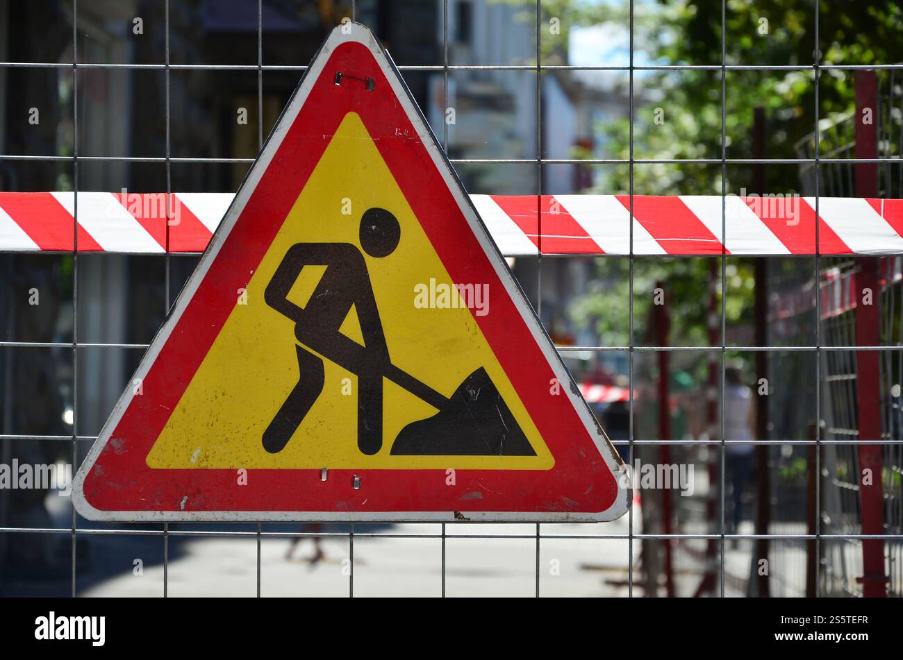 The warning sign "under construction" is attached to a metal mesh fence ...