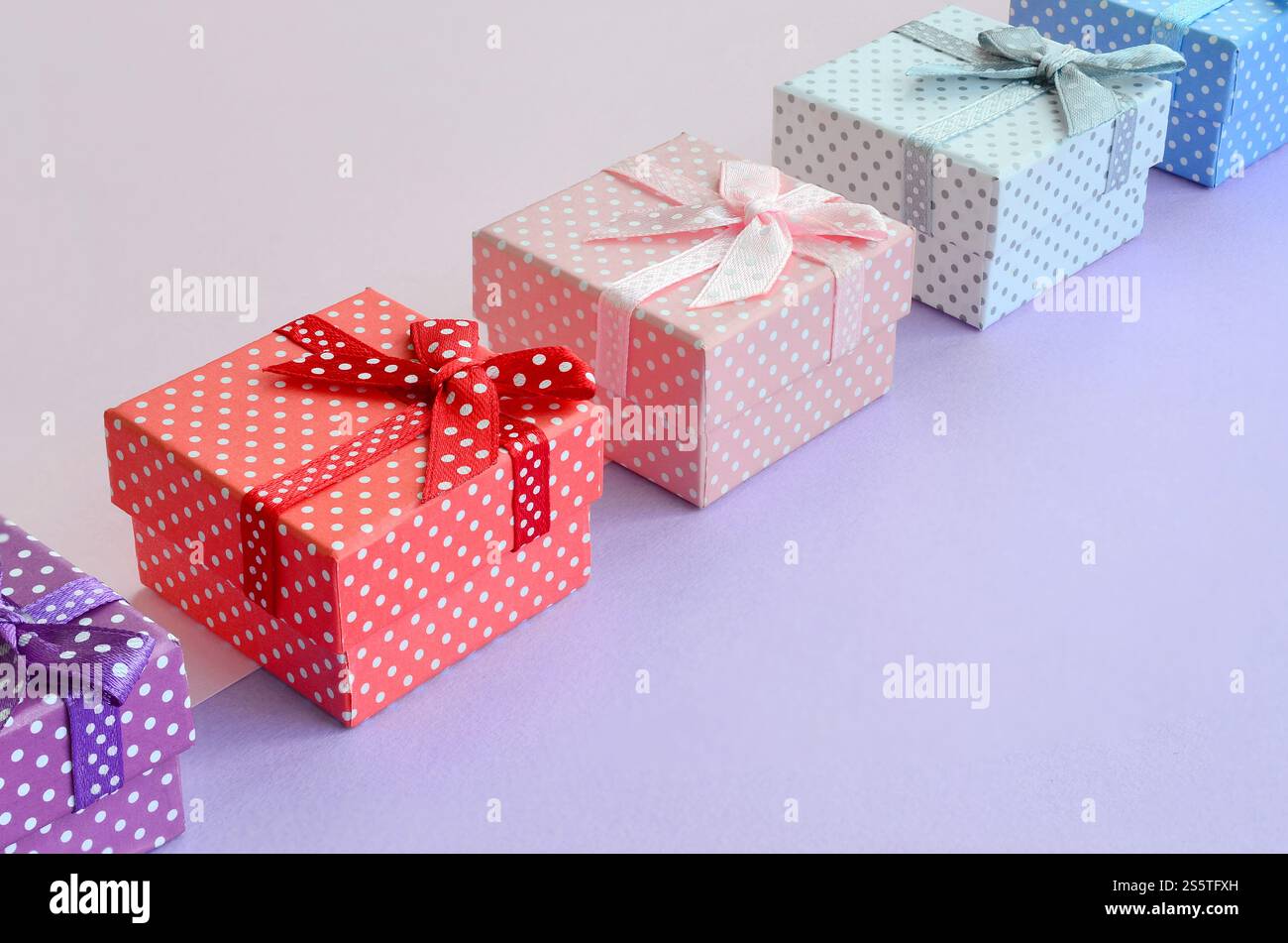 Small gift boxes of different colors with ribbons lies on a violet and ...