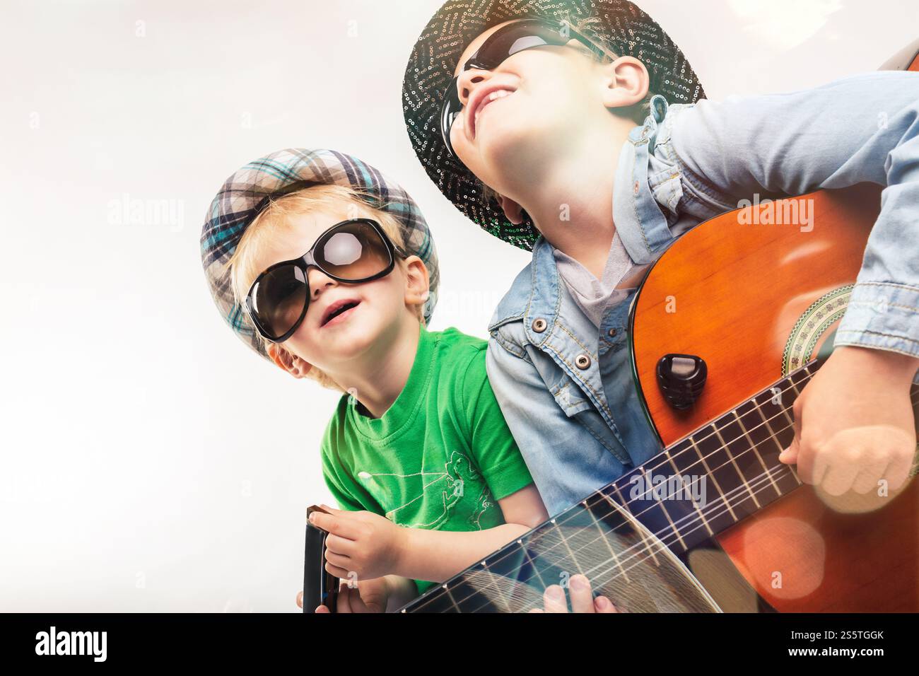 Two young boys are having fun playing musical instruments, one playing ...