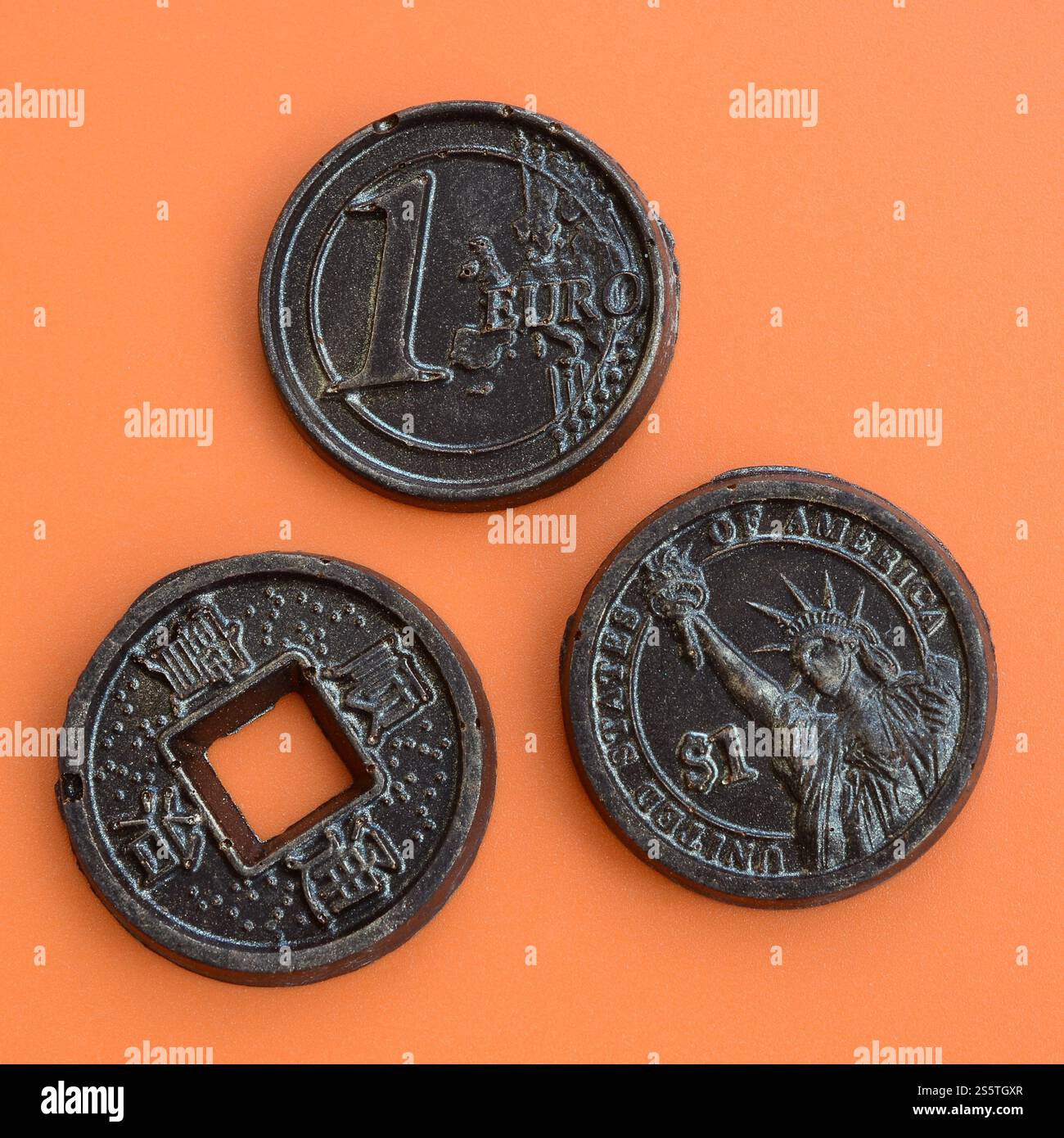 Three chocolate products in the form of Euro, USA and Japan coins lie ...