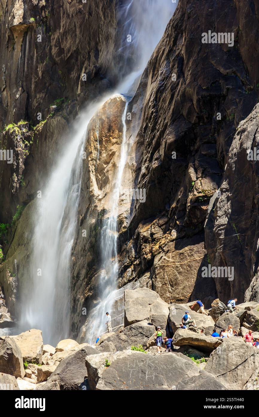 A group of people are gathered around a waterfall, enjoying the natural ...