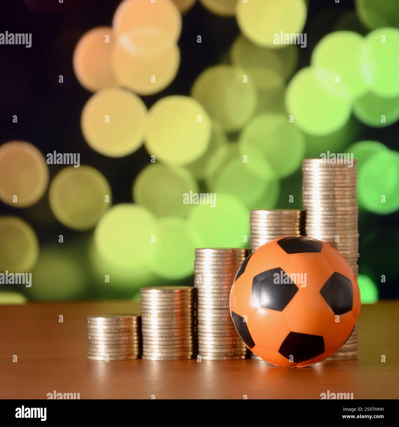 Soccer ball and stacks of golden coins in growth graph on the blurred ...