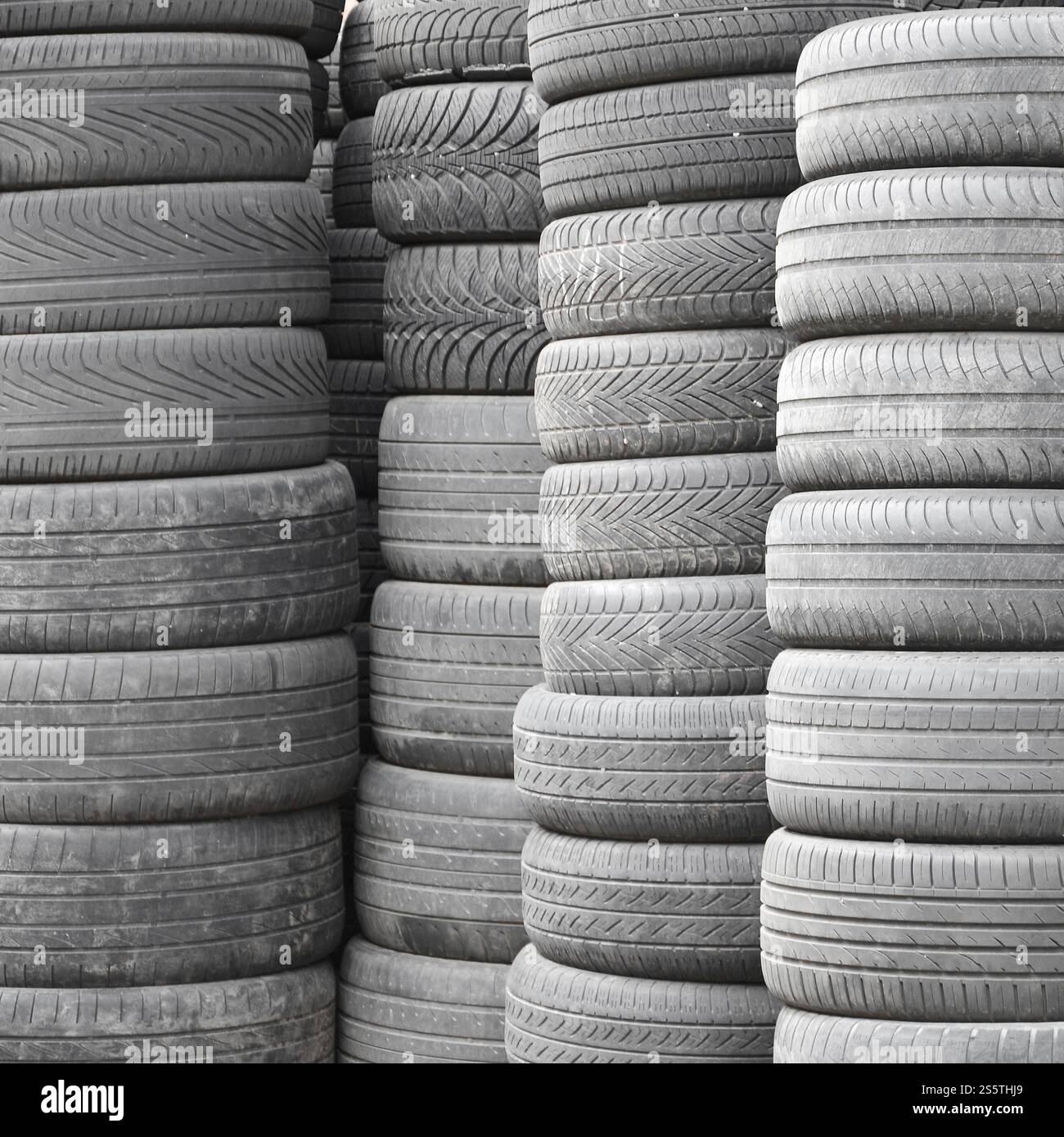 Old used tires stacked with high piles in secondary car parts shop ...