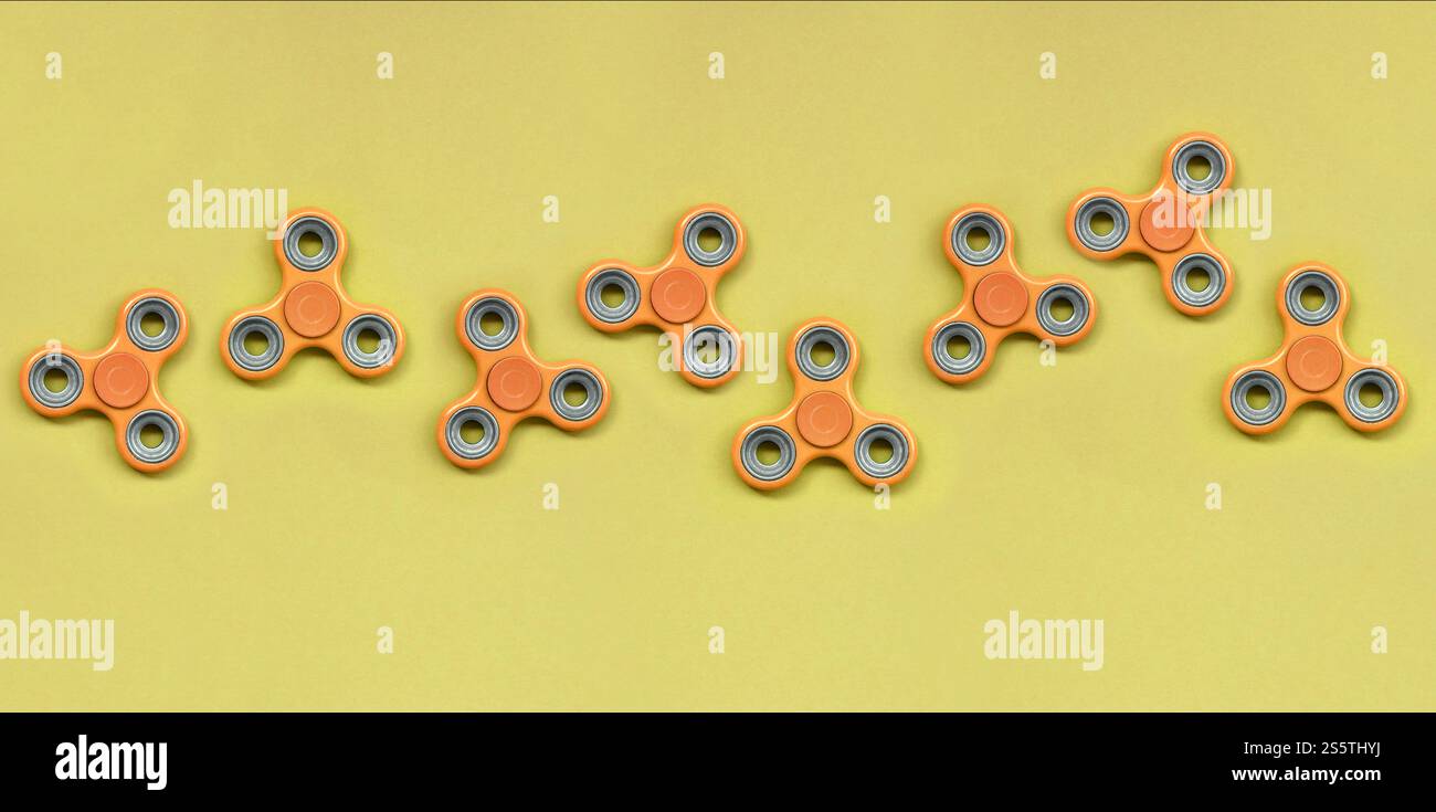 Many orange fidget spinners lies on texture background of fashion ...