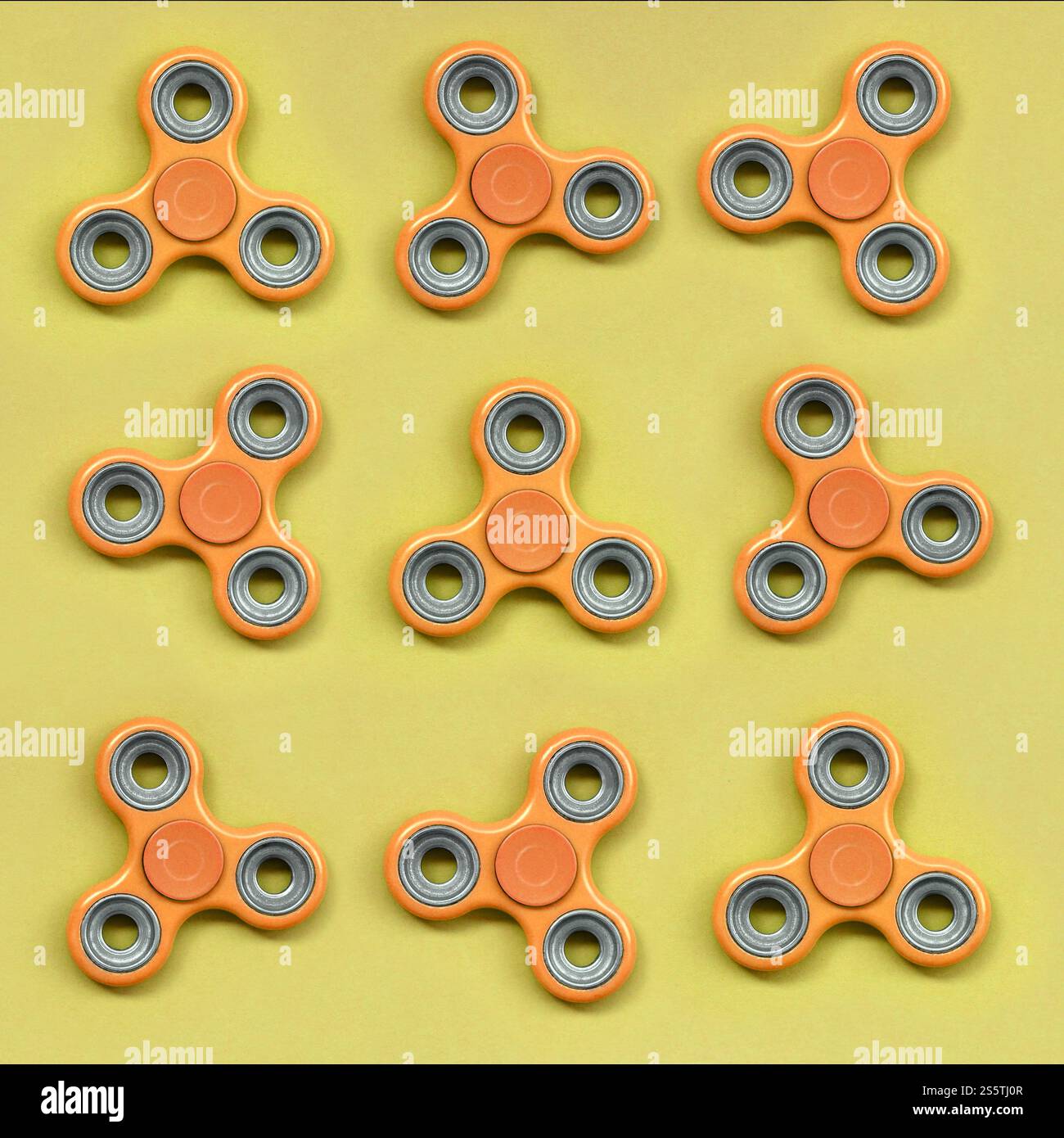 Many orange fidget spinners lies on texture background of fashion ...