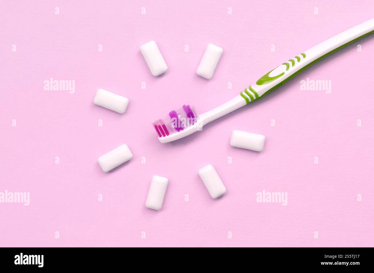 Toothbrush and chewing gums lie on a pastel pink background. Top view, flat lay. Minimal concept ...
